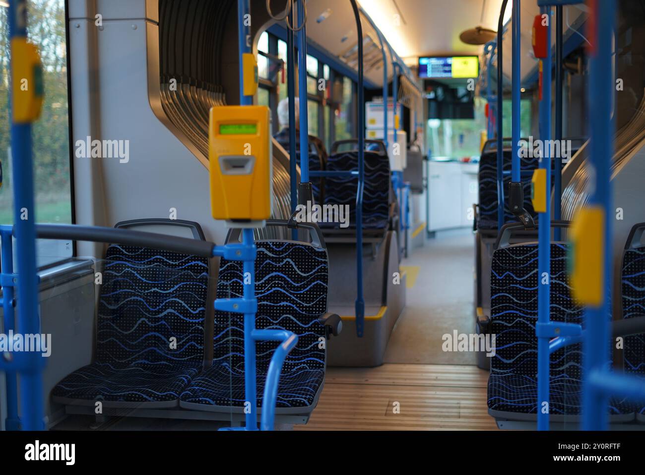 interior of a modern bus, featuring patterned blue seats, yellow ticket ...