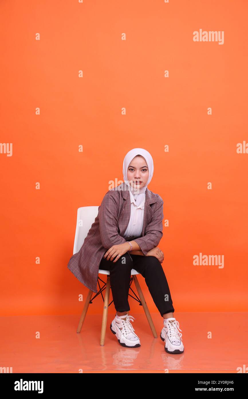 Full length portrait of young Muslim Asian girl sitting in elegant ...