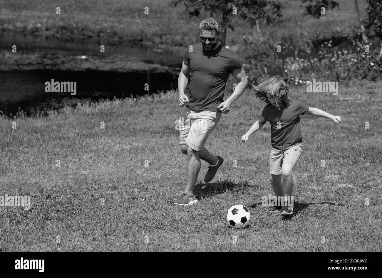 Father and son playing football in park. Dad and little boy play soccer ...