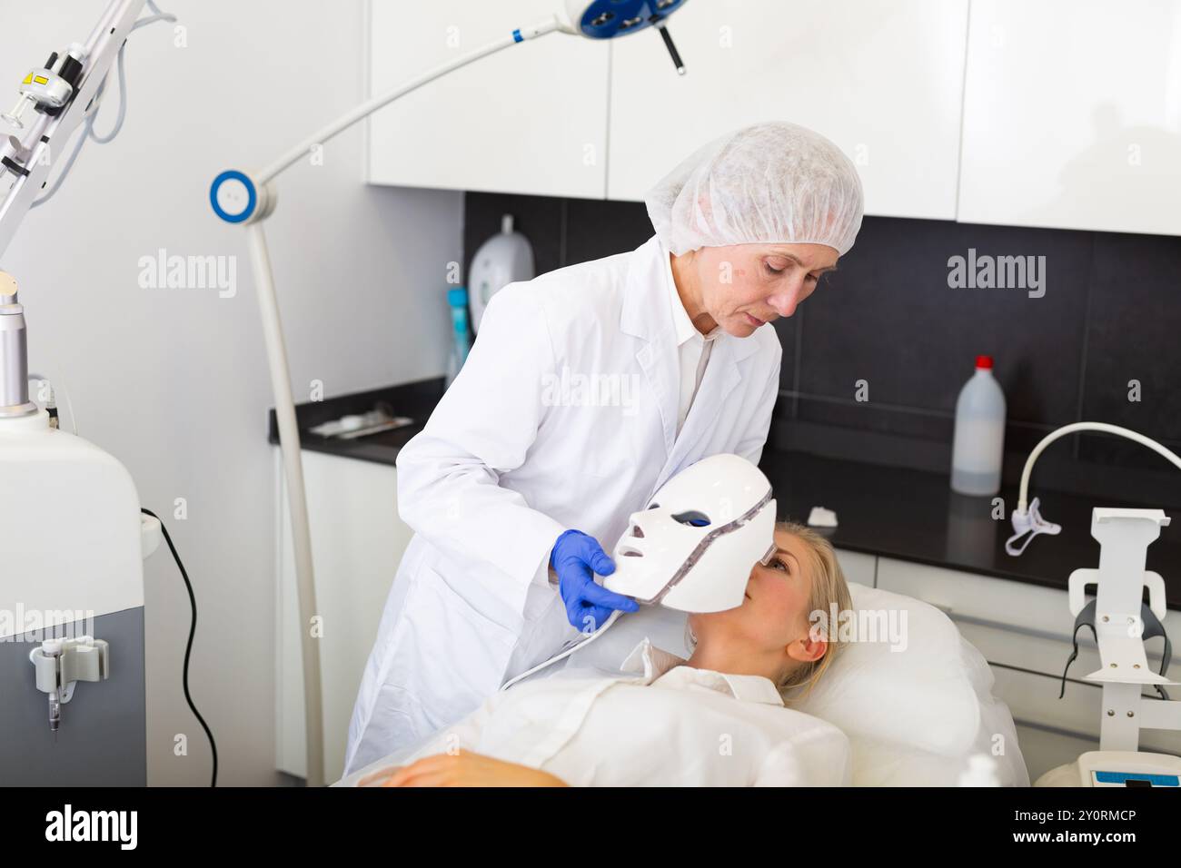 Young woman receiving facial light therapy in aesthetic medicine office ...
