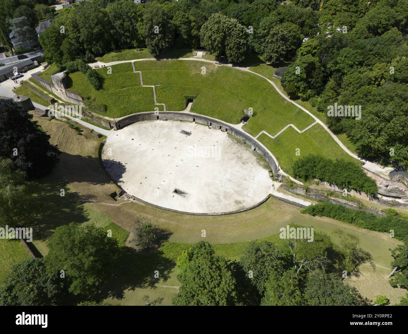 Aerial view of an ancient theatre surrounded by lush greenery and trees ...