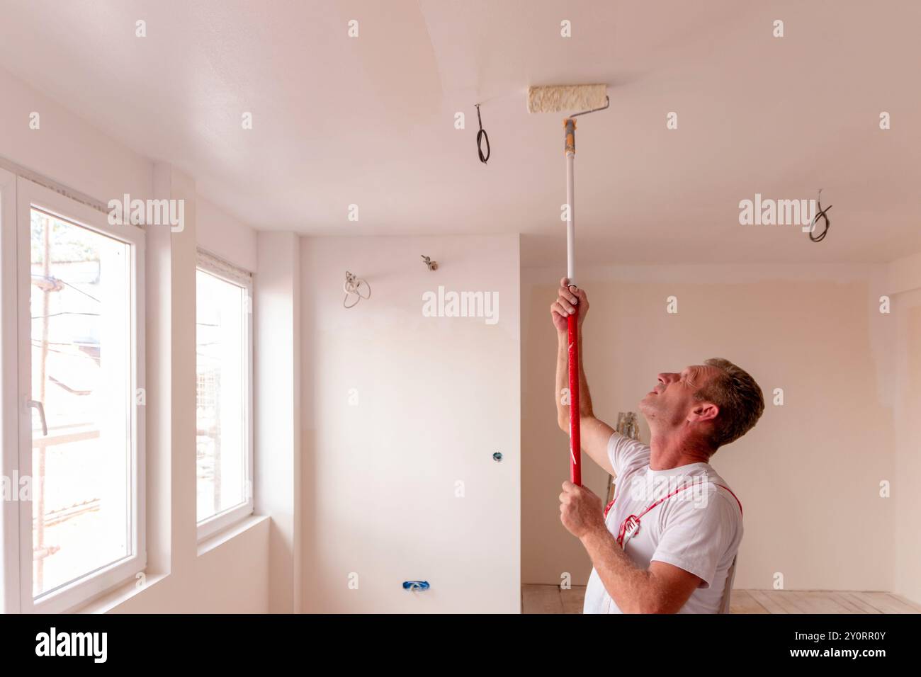 Construction worker painter man with paint roller in his hand and ...