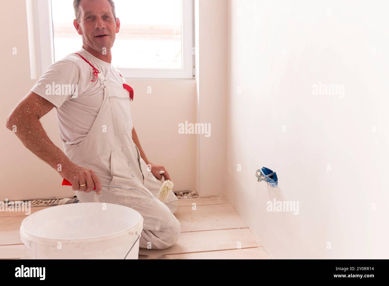 Construction worker painter man with paint roller in his hand and ...