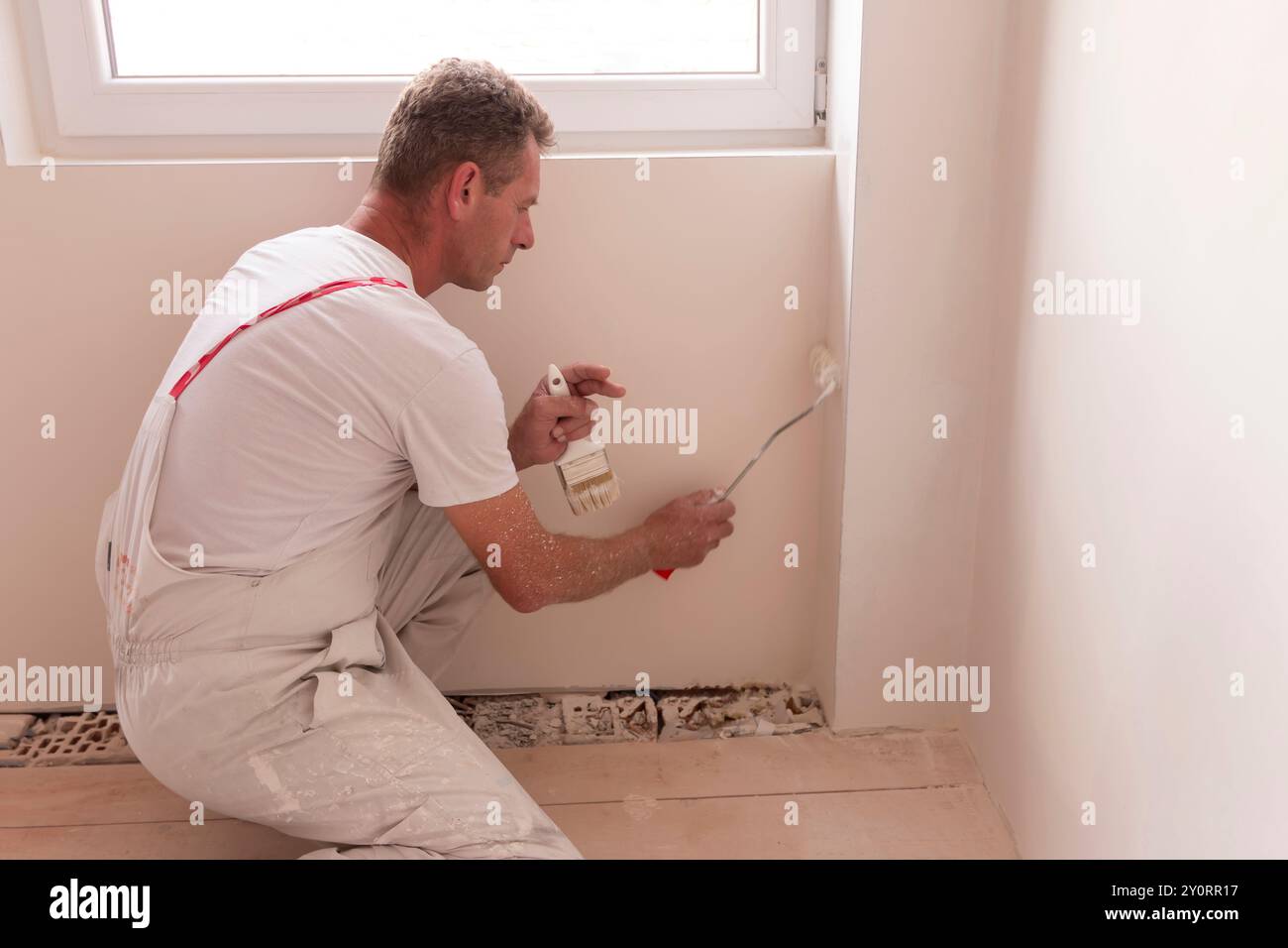 Construction worker painter man with paint roller and brush in his hand ...