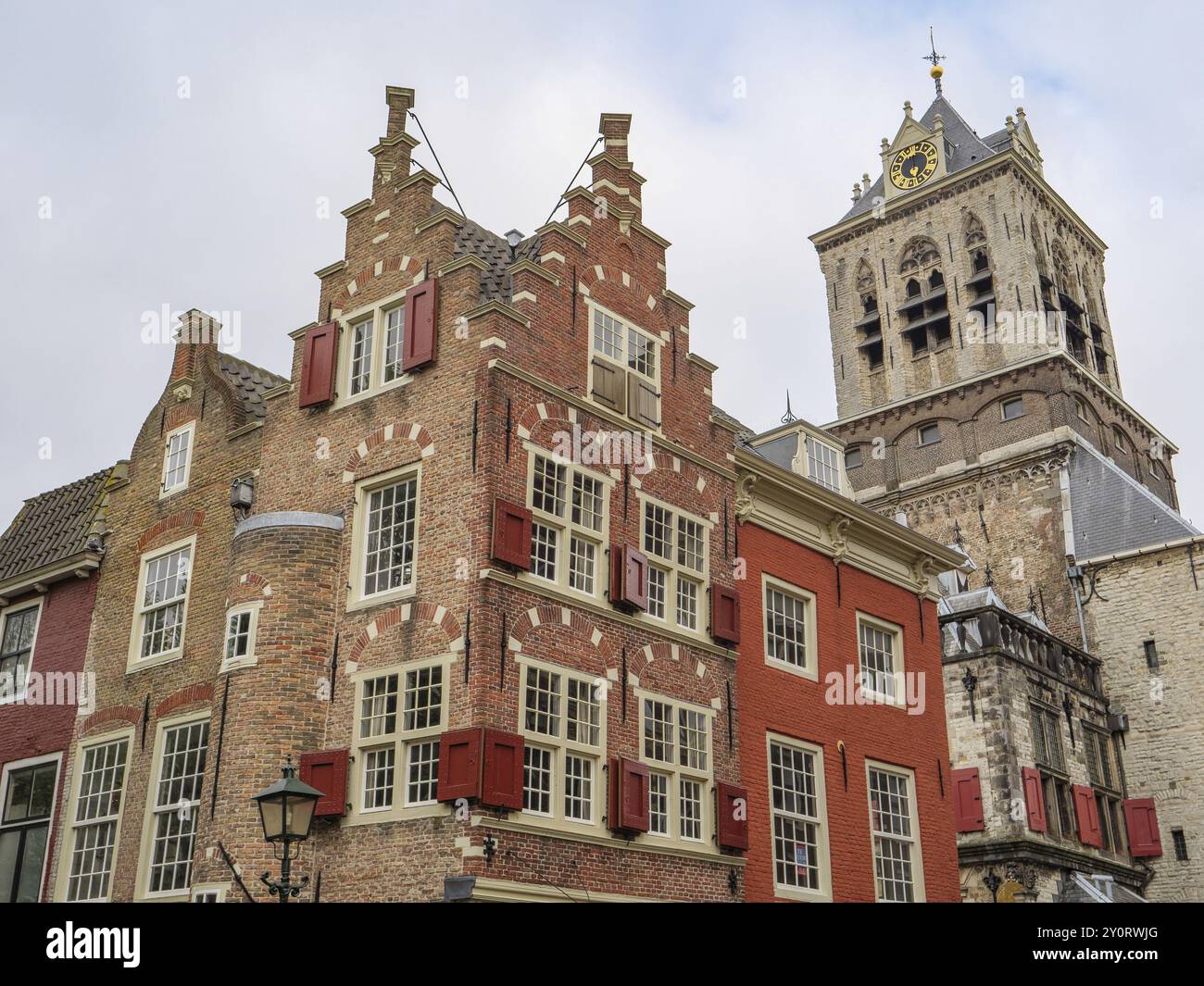 Historic gabled houses with red shutters below an old church tower ...