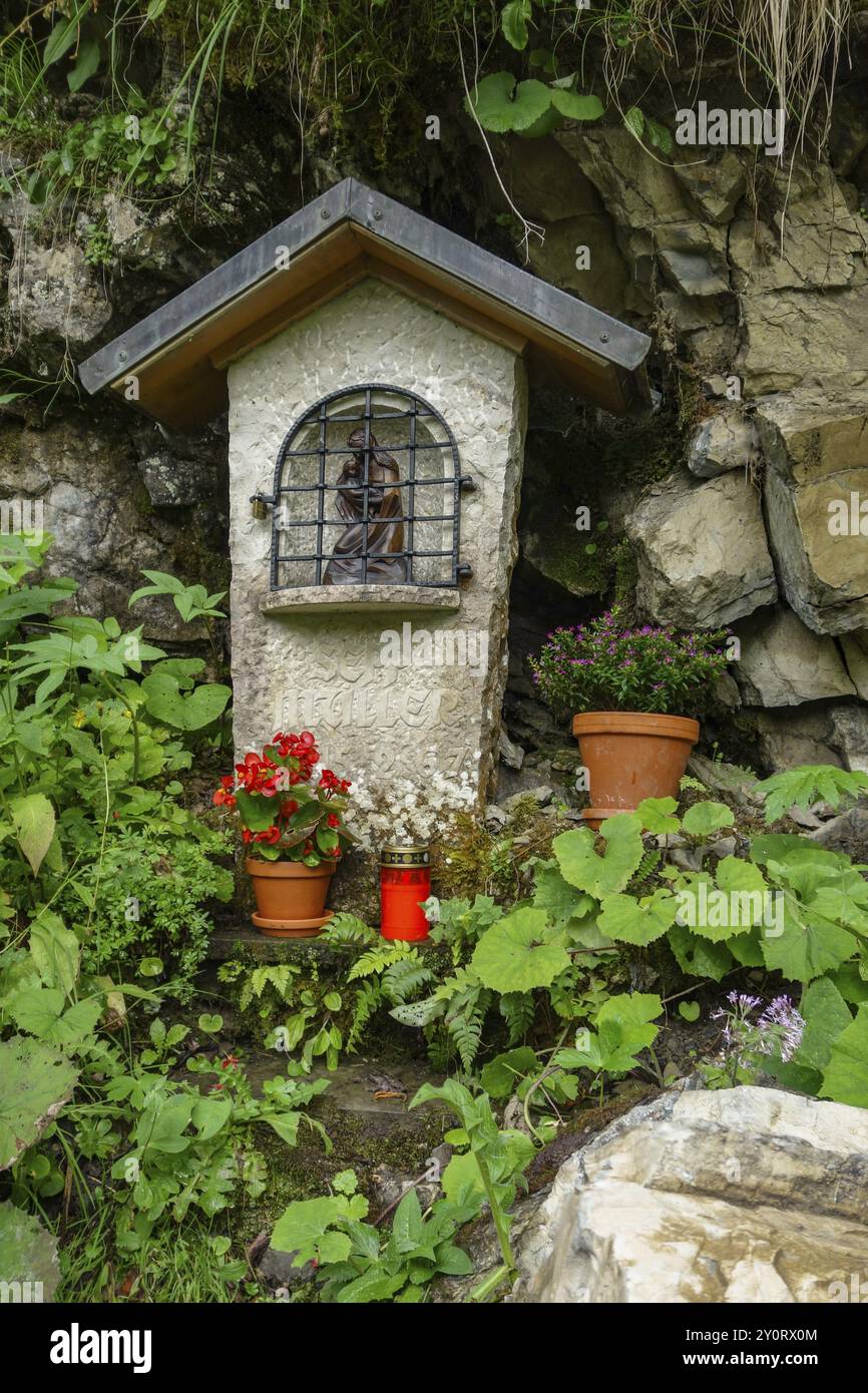 A small shrine with flowers and religious symbols is integrated into a ...