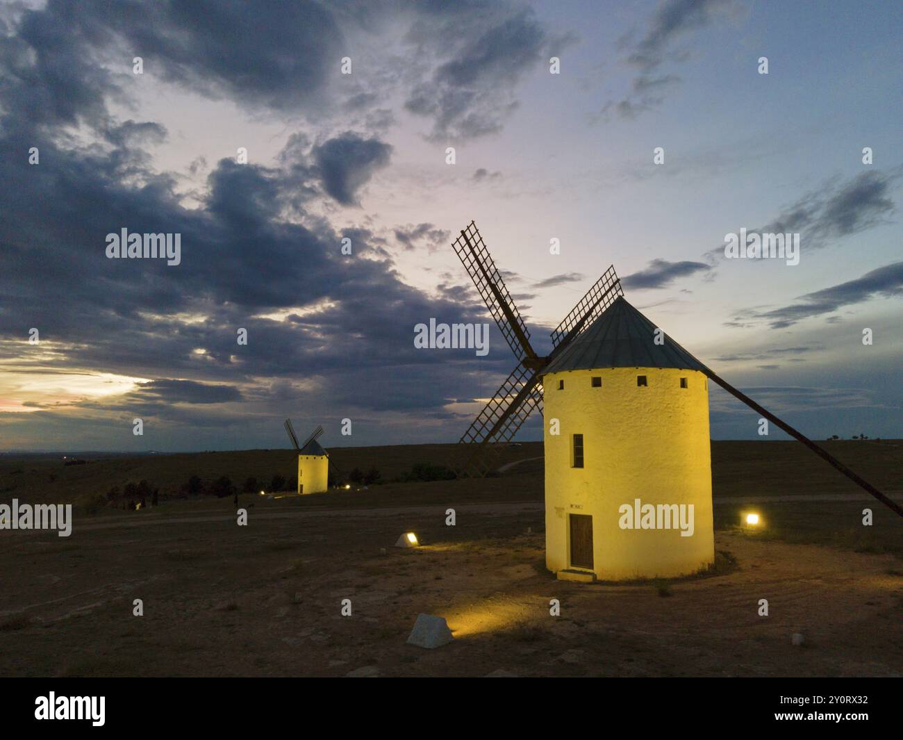An illuminated windmill at night under a cloudy sky. The surroundings ...