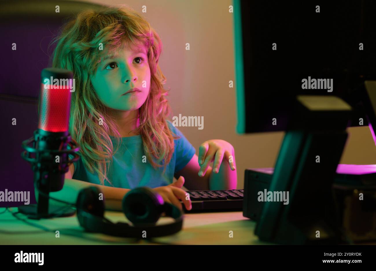 Kid using pc at night. A pretty child learns a lesson using a desktop ...
