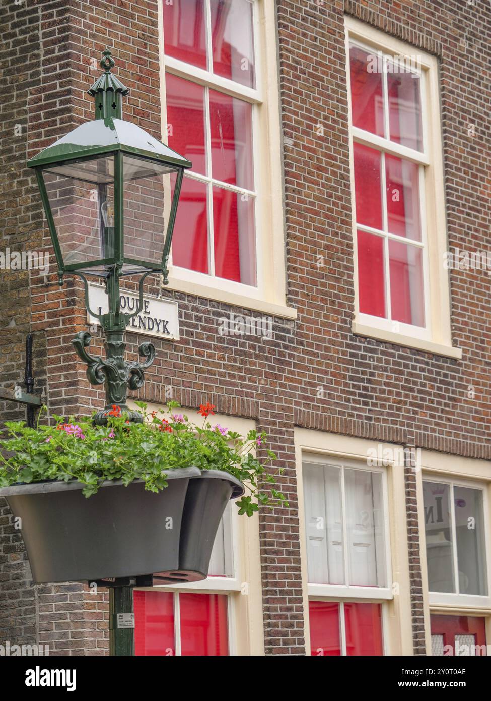 Historic street lamp with flower box in front of window with red blinds ...