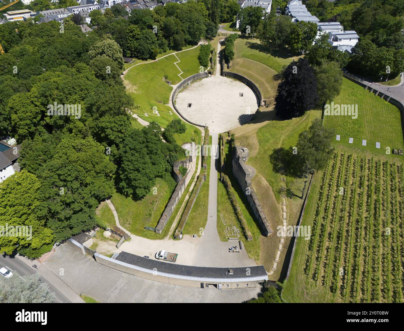 Aerial view of an ancient amphitheatre, surrounded by dense greenery ...
