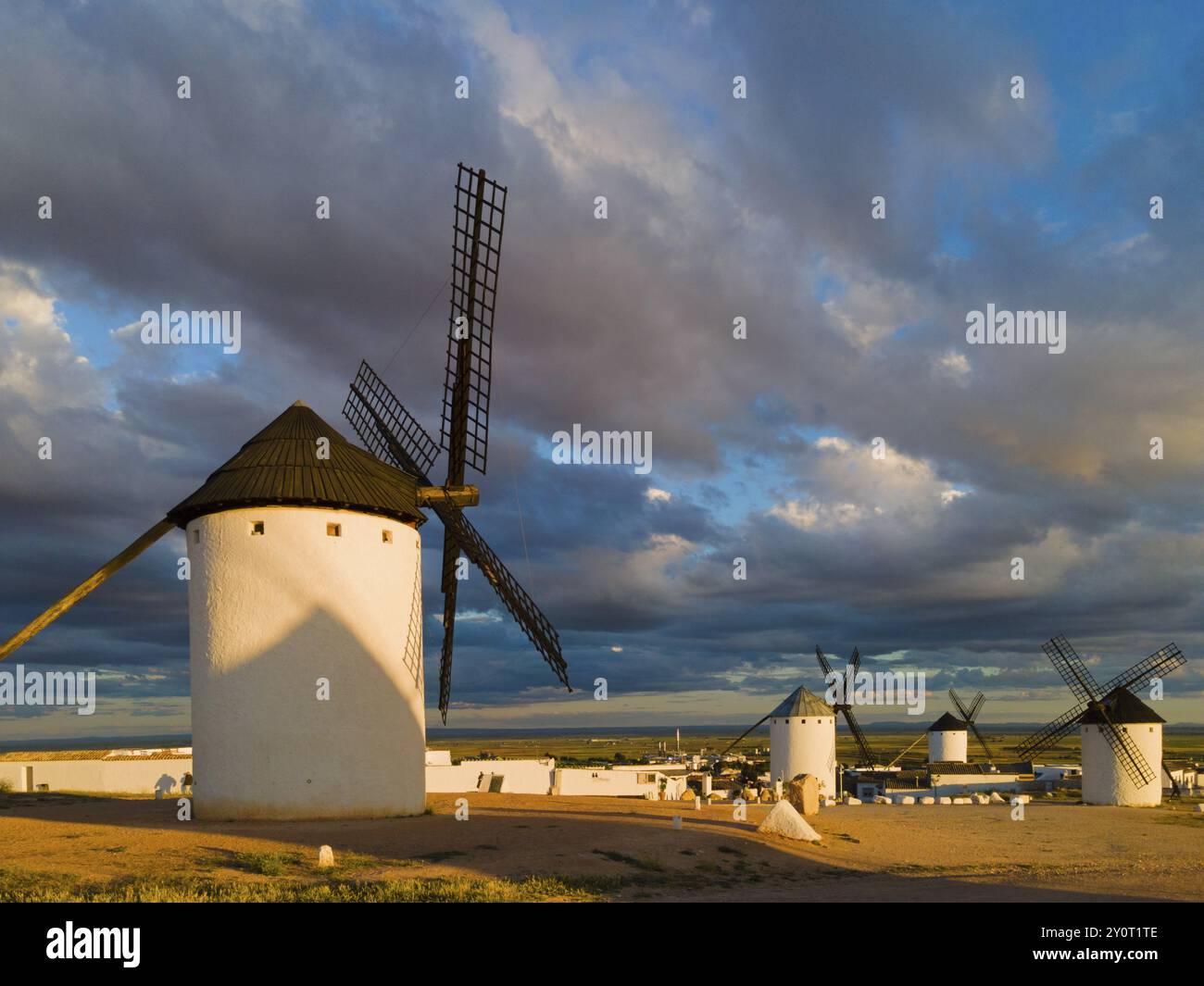 White windmills in an open landscape with dramatic clouds and sunbeams ...