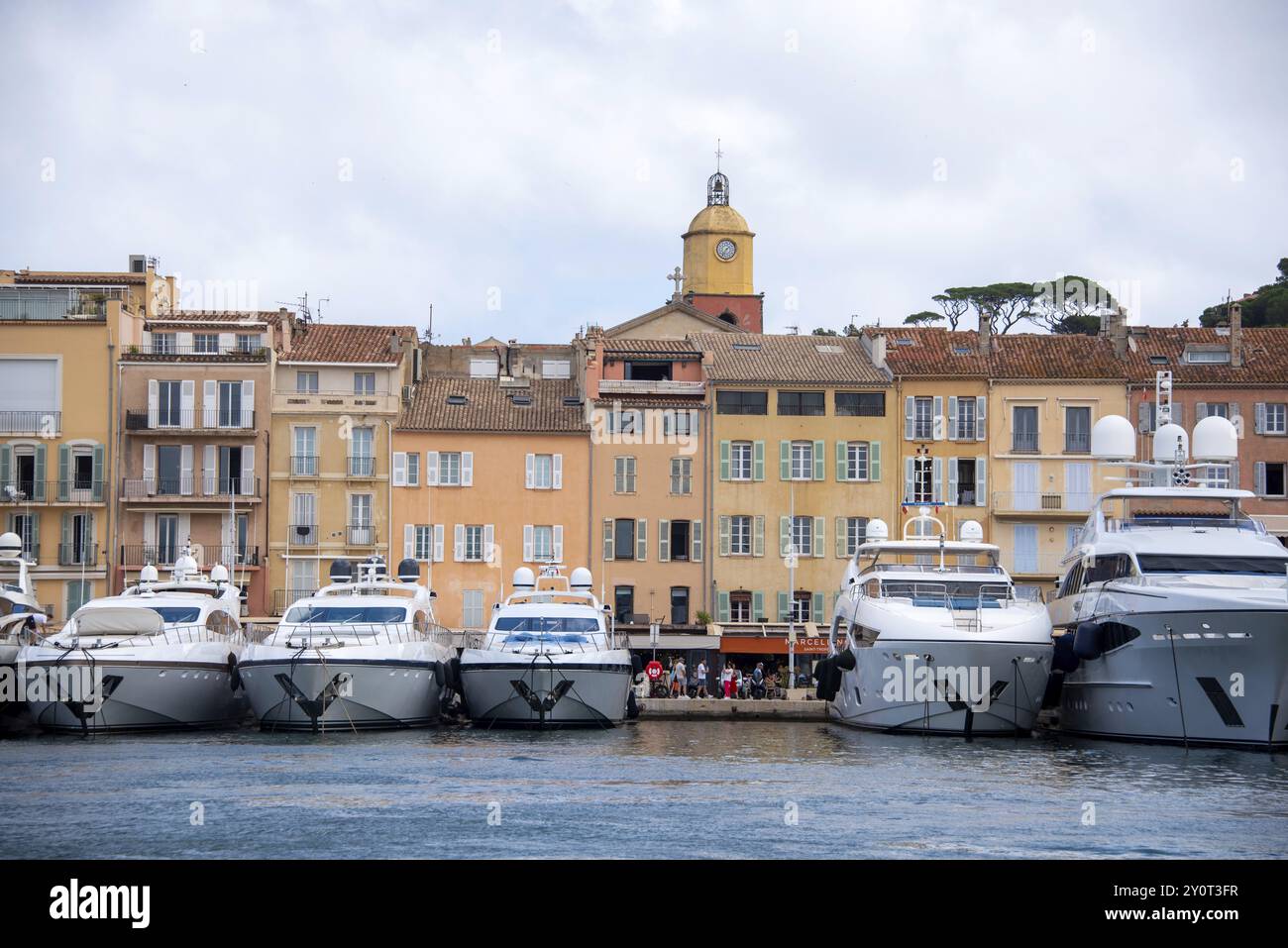 Yachts moored in the harbour of Saint Tropez, behind them colourful ...
