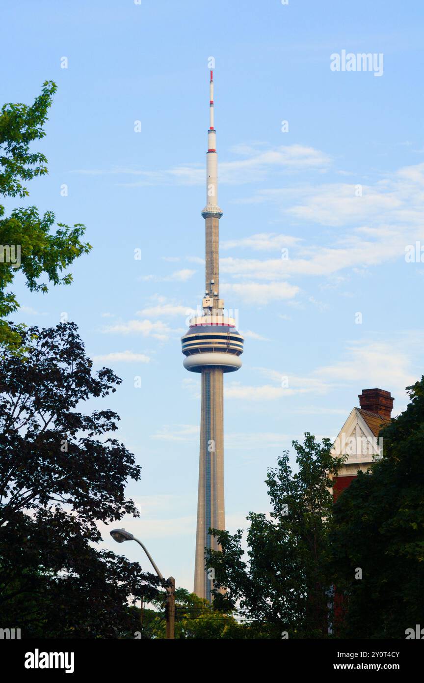 A view of the CN Tower in Toronto framed by green trees and residential ...