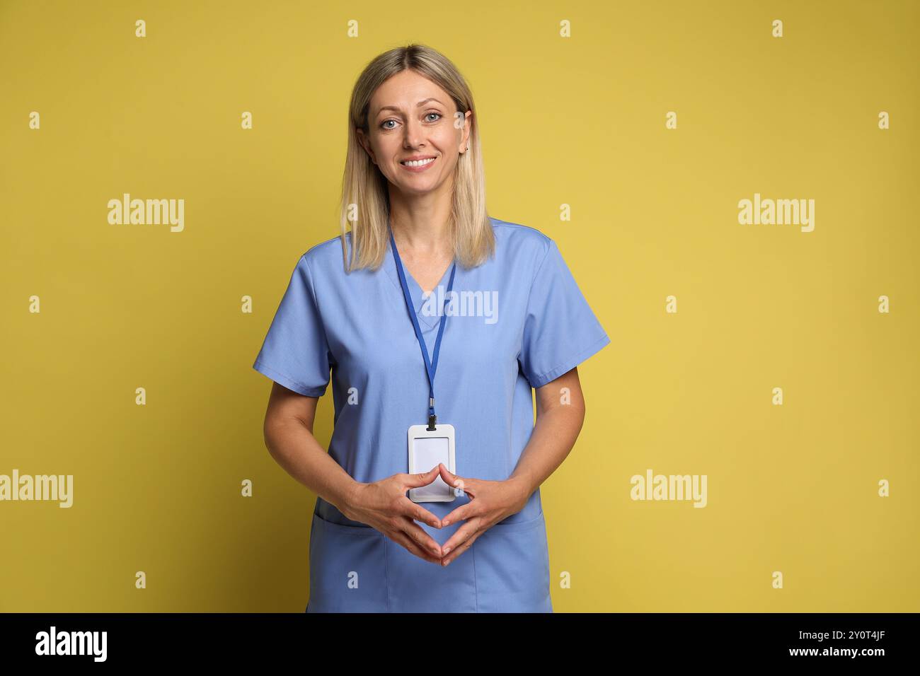 Portrait of nurse in medical uniform with badge on yellow background ...