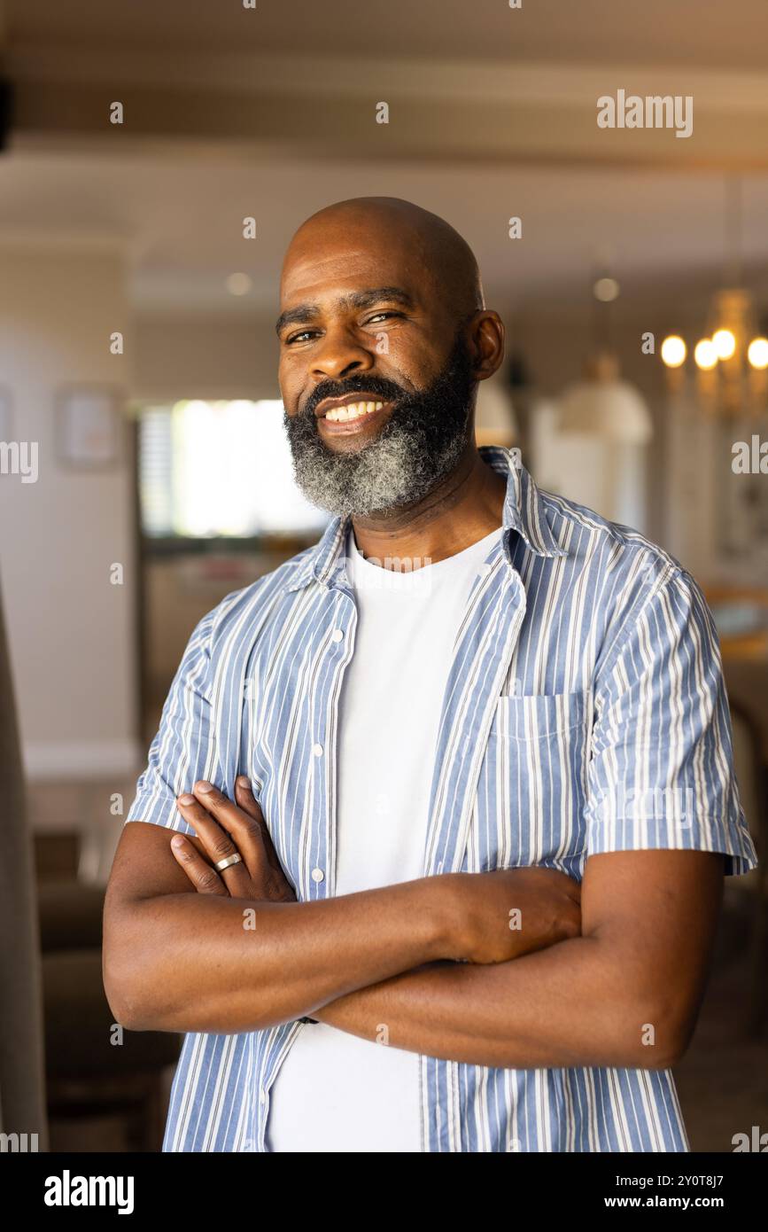Smiling african american senior man with crossed arms standing confidently in modern home Stock ...