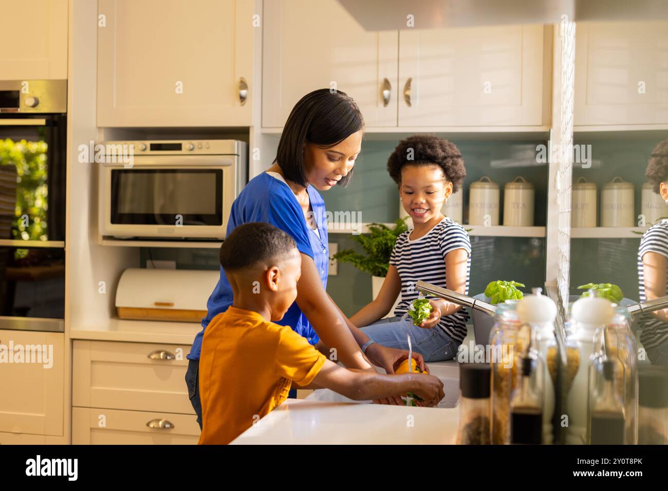 Washing vegetables together, mother and children in modern kitchen ...