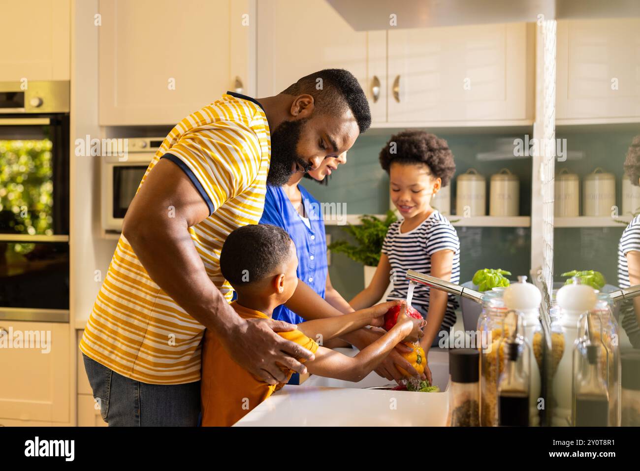 Family washing vegetables together in kitchen, bonding and preparing ...