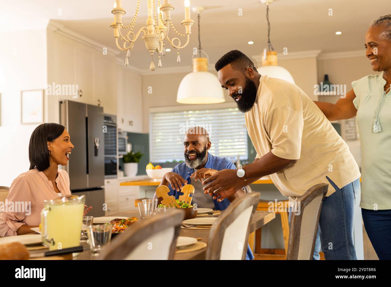 Serving food at dining table, multi-generational family enjoying meal ...