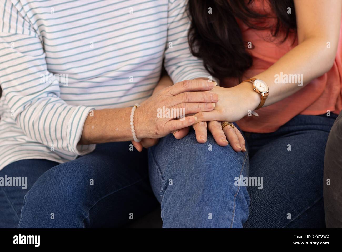 Holding hands, two women sitting closely, showing support and affection ...