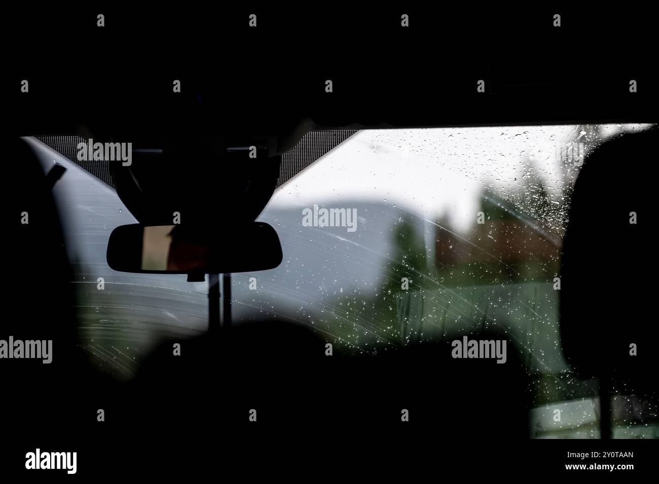 Obstructed view from the back seat of a vehicle with rain falling on ...