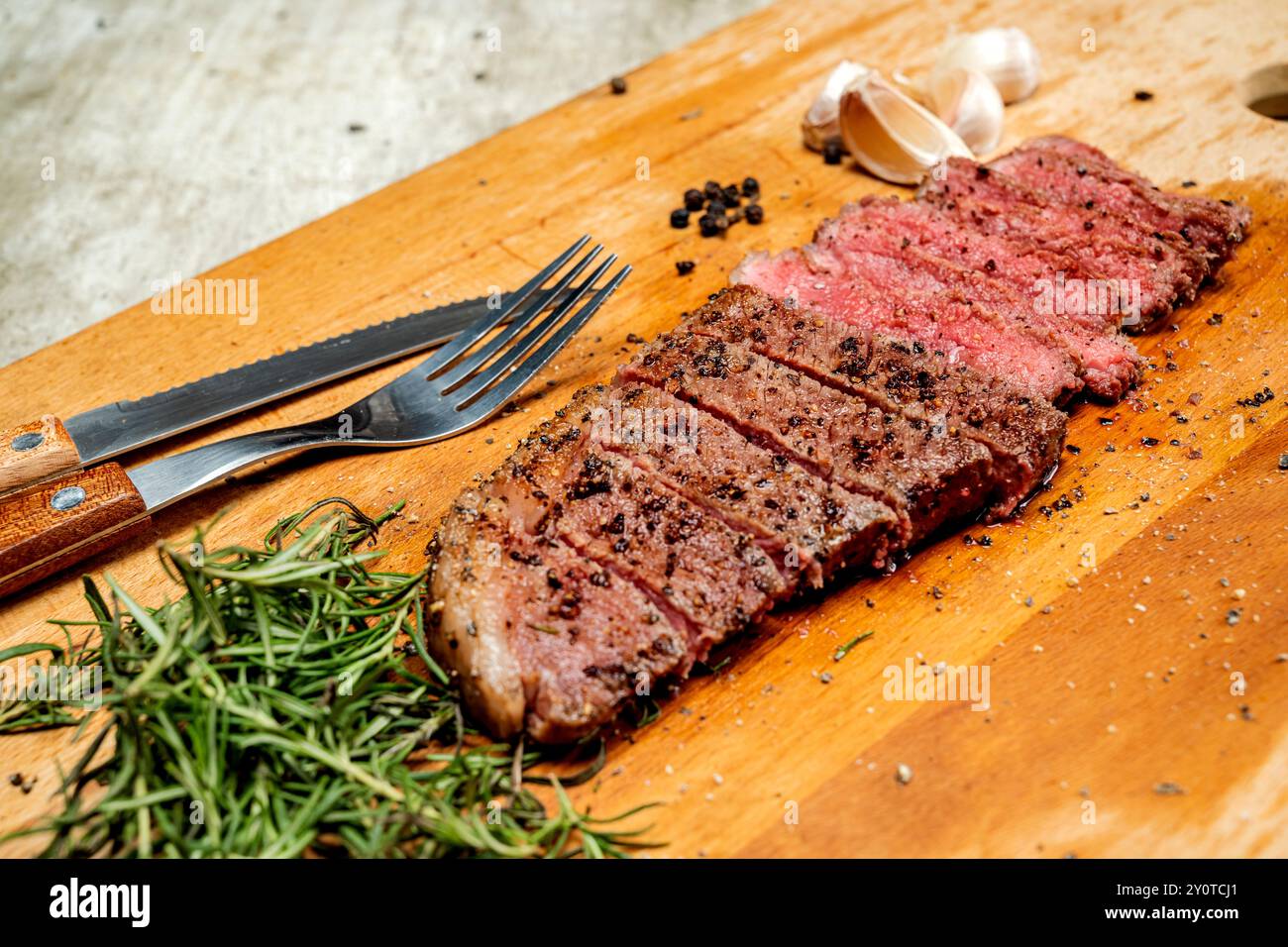 A piece of picanha meat is cut and sitting on a wooden cutting board ...
