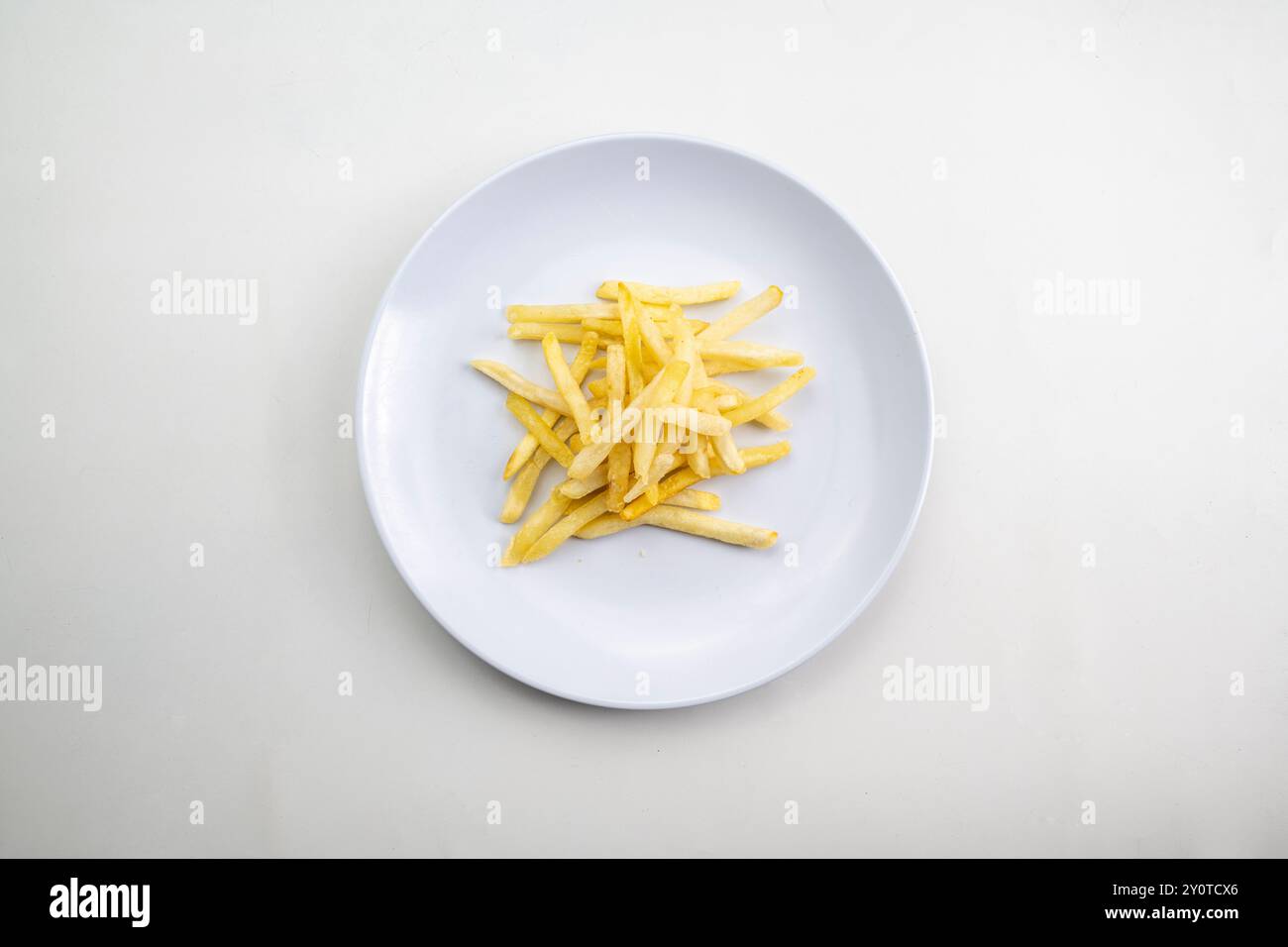 A plate of french fries sits on a white table. The plate is empty and ...