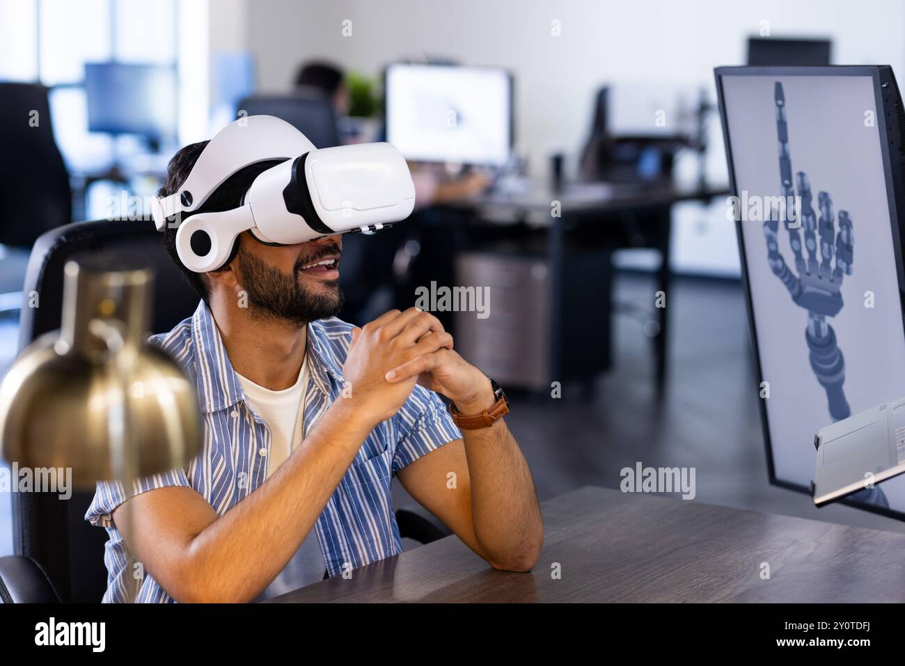 Using VR headset, Indian man interacting with robotic hand design on ...
