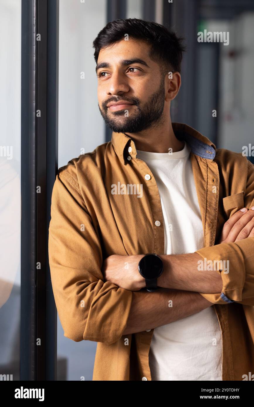Confident Indian man in casual attire standing with arms crossed in ...