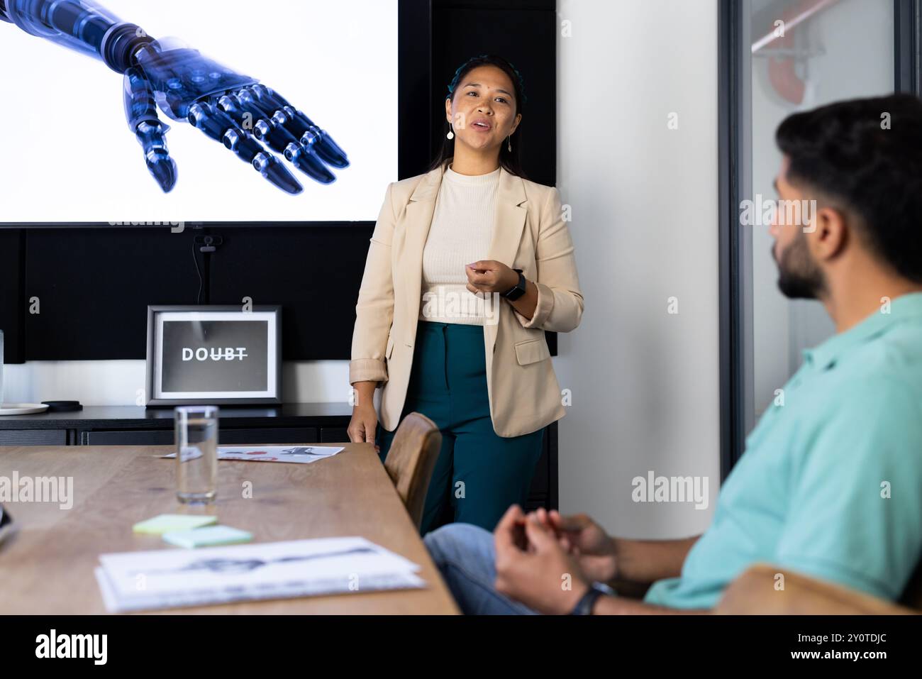 Presenting in office, woman discussing robotic arm with colleague ...