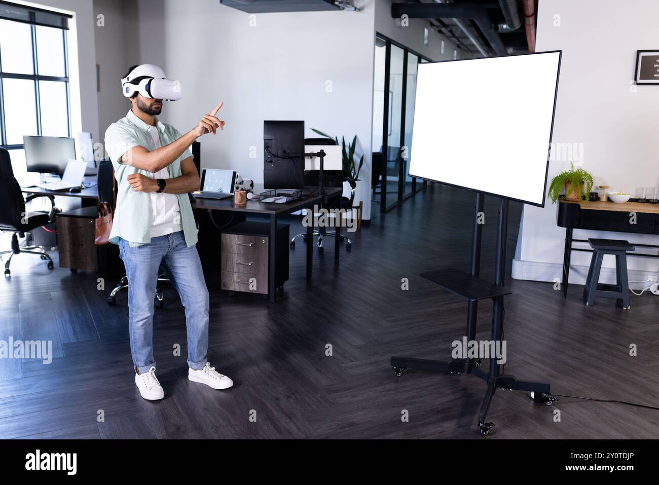 Using VR headset, Indian man interacting with virtual screen in modern ...