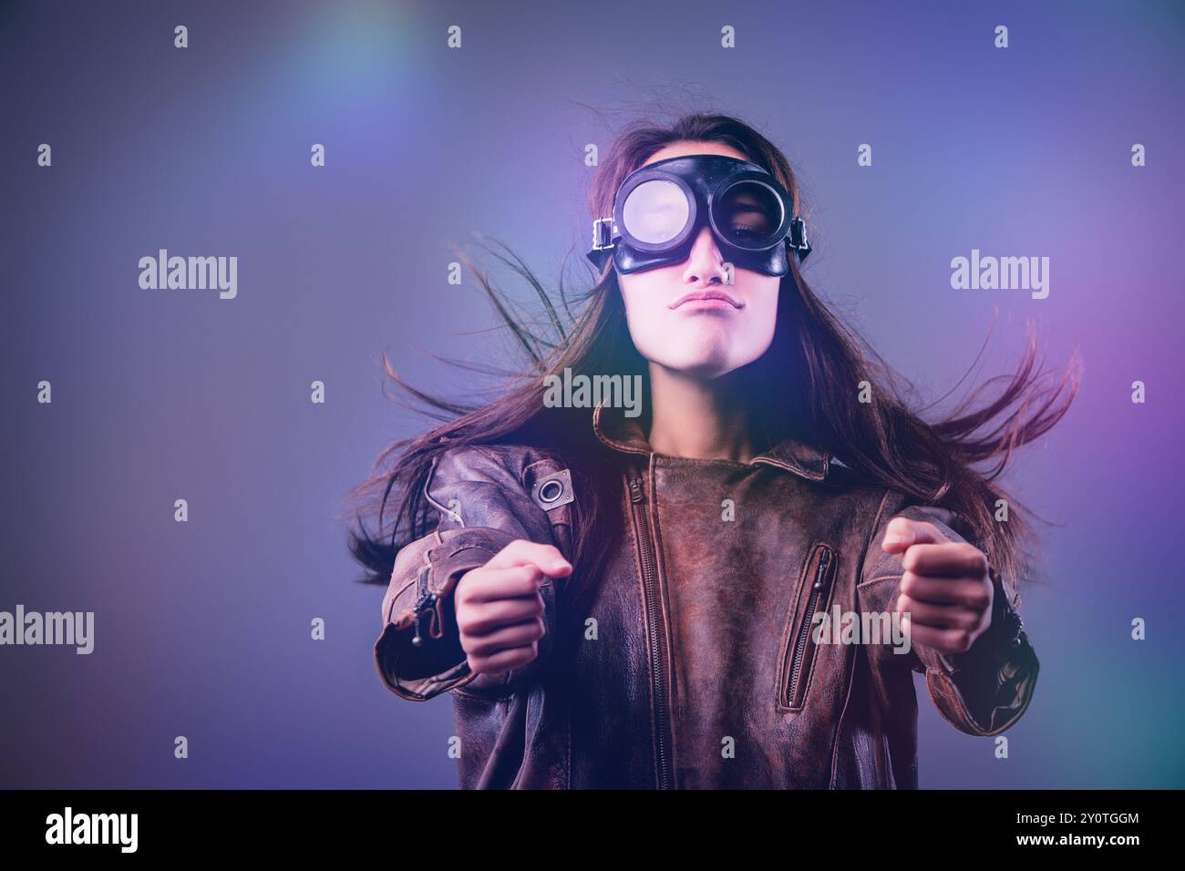 Carefree young woman in her twenties poses playfully in a colorful studio setting. Wearing ...