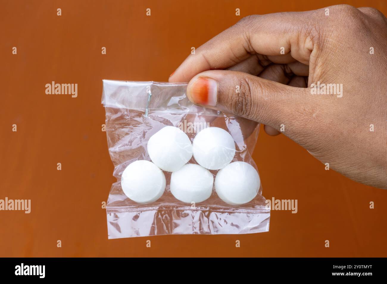 A female hand holding packet naphthalene balls packet, also known as ...