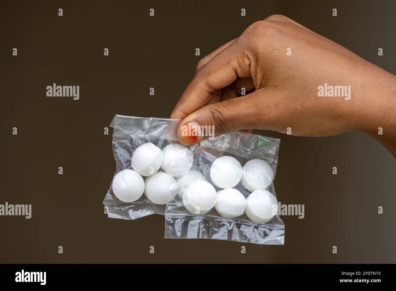 A female hand holding two naphthalene balls packets, also known as ...