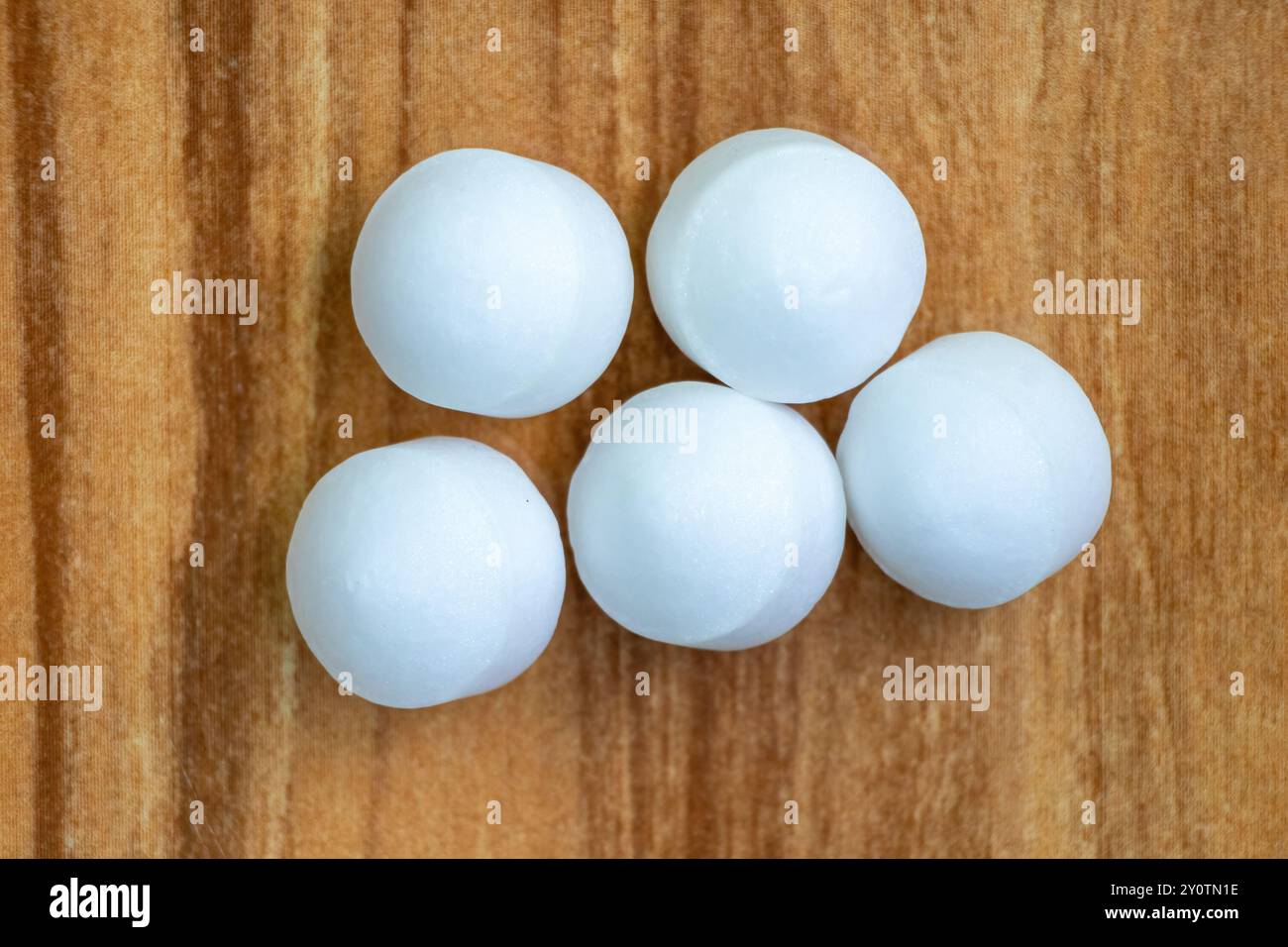 White Naphthalene balls on wooden background. It is also known as ...