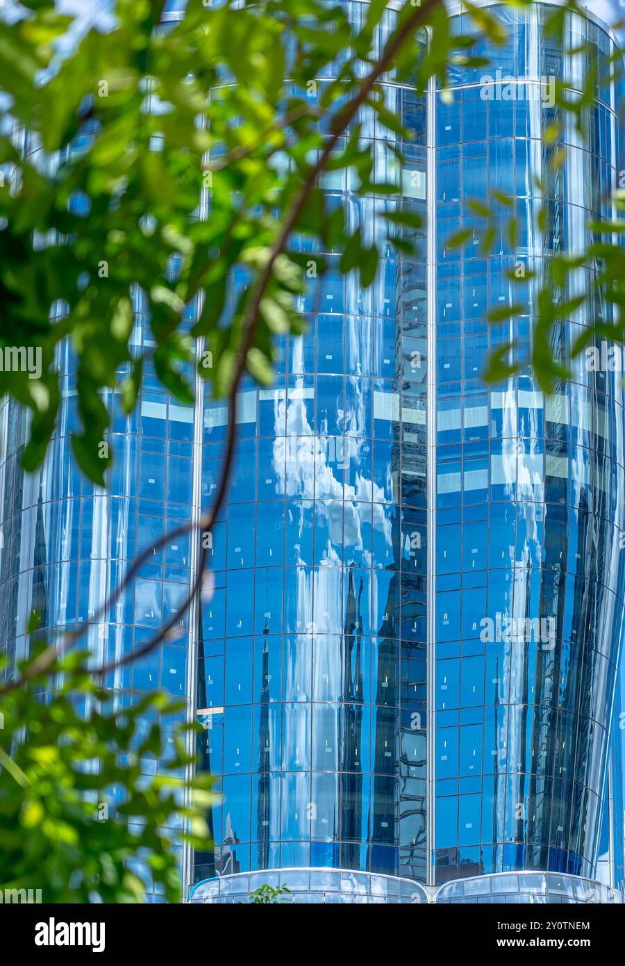 A modern building with a curved facade and blue glass windows reflects ...