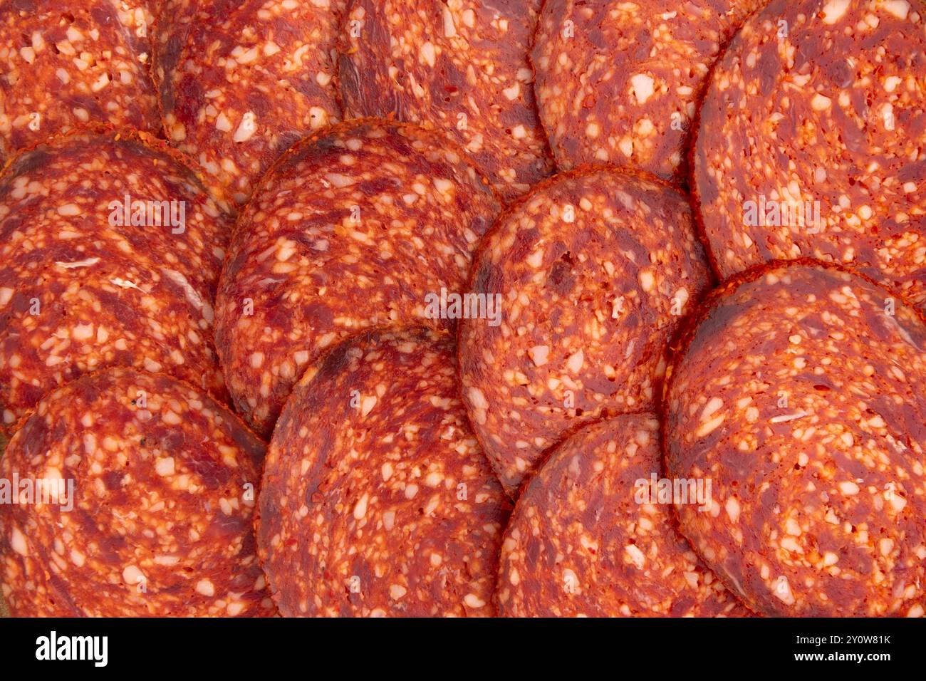 smoked sausage salami with paprika cut into pieces as background ...