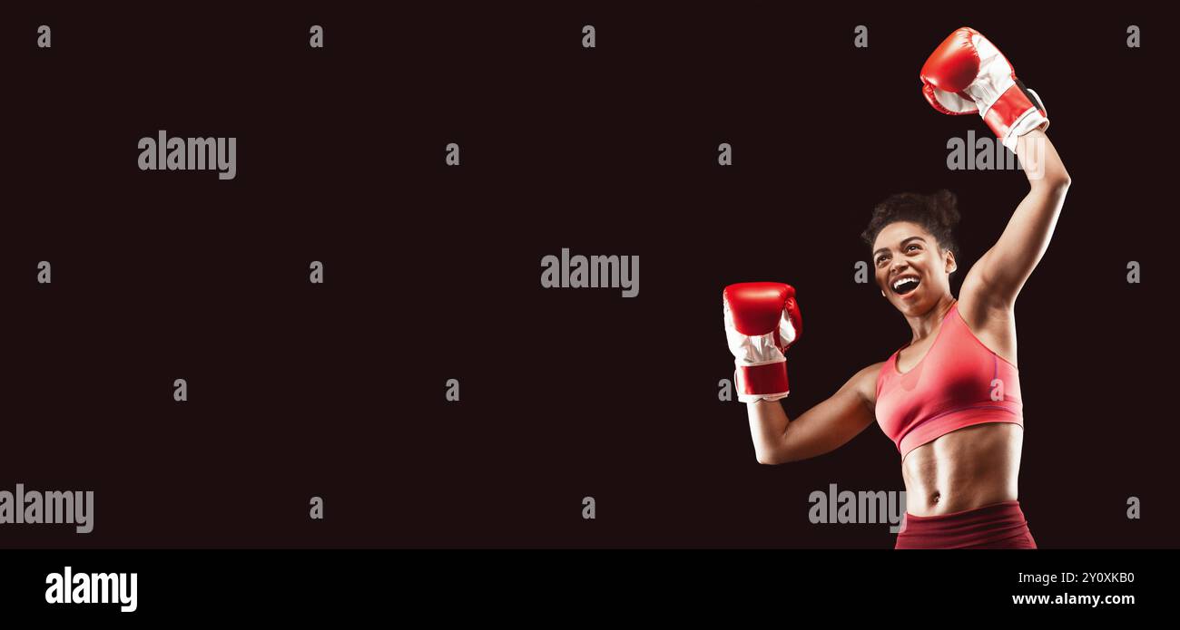 Emotional afro girl boxer celebrating success over black background ...