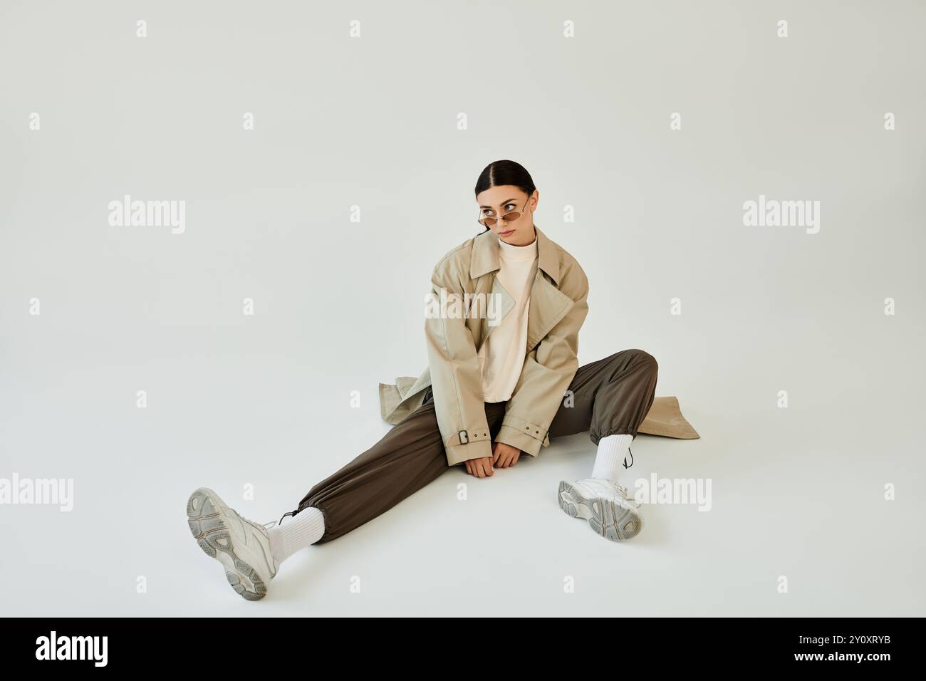 A young woman poses confidently in a trendy autumn outfit, showcasing a ...