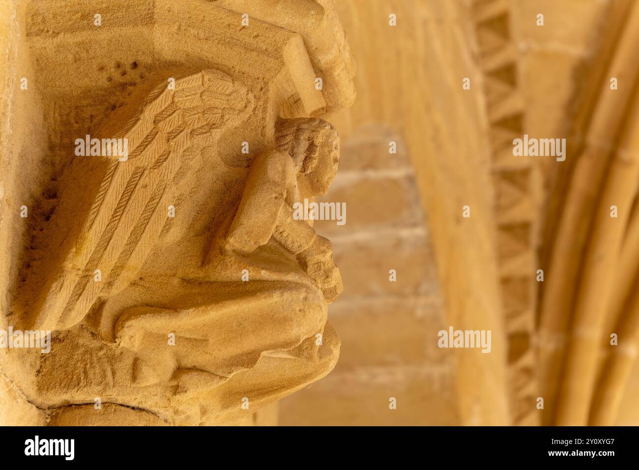 A statue of an angel kneeling with his hands on his knees. The statue ...