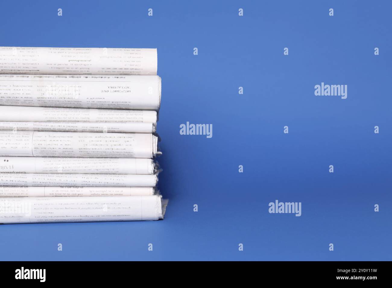 Stack of newspapers in different languages on blue background, space ...