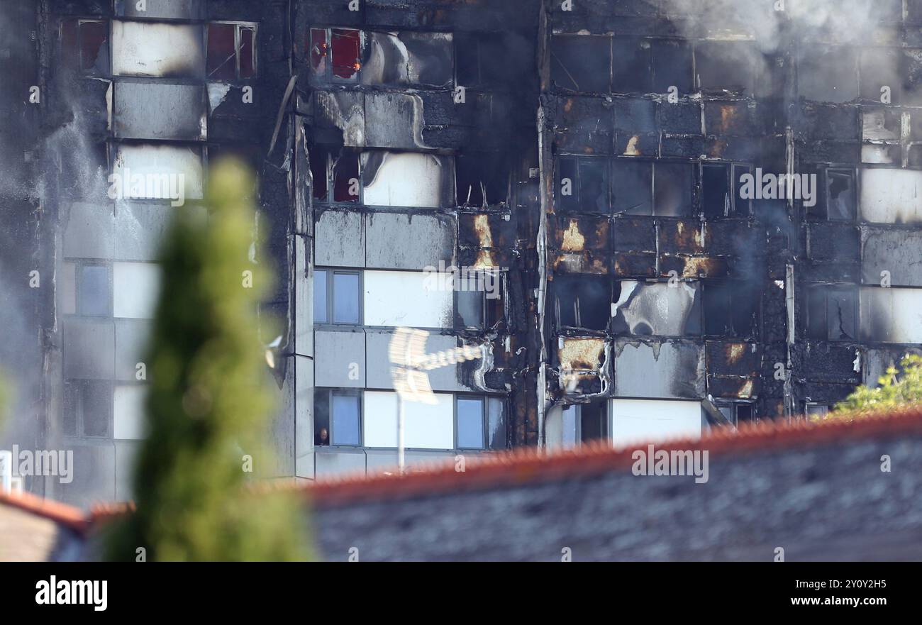 File photo dated 14/07/2017 of a man looks from a window as smoke pours ...