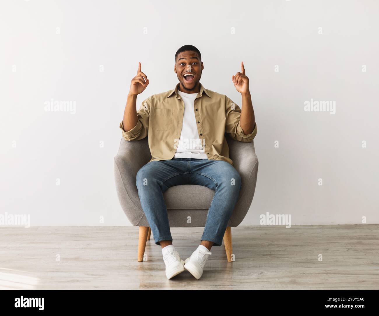 Excited African Millennial Man Pointing Fingers Up Sitting, Gray ...