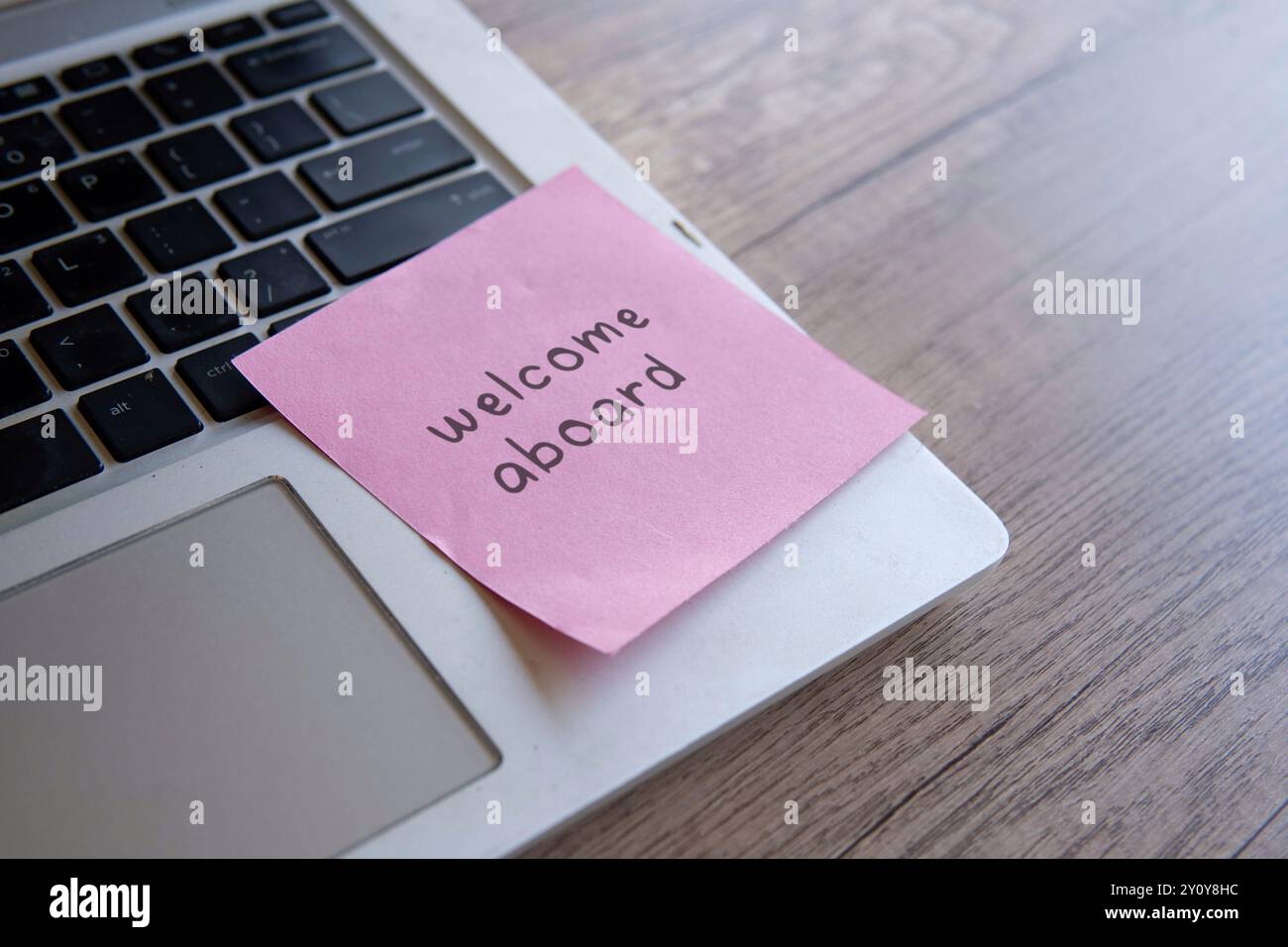 A close-up of a laptop keyboard with a pink sticky note attached with ...