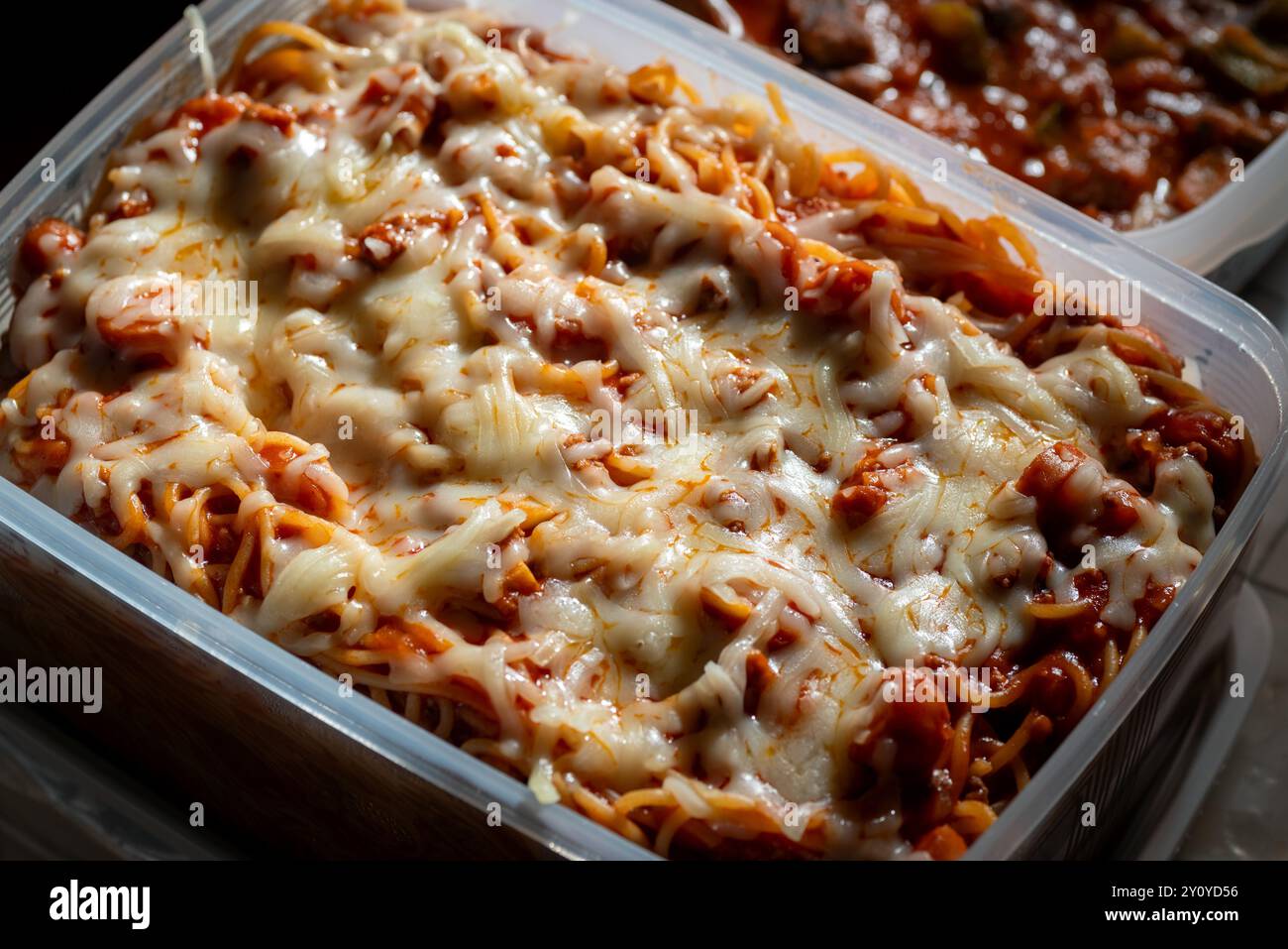 Filipino spaghetti with melted cheese on top in a plastic food tub ...