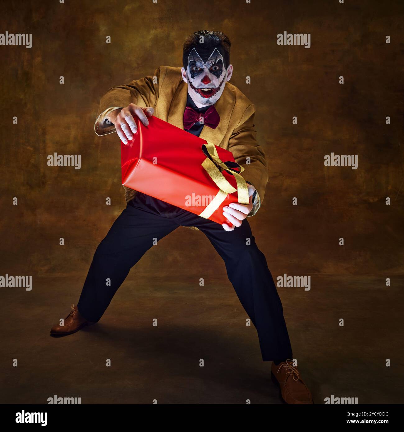 Crouched low with red gift, the clown looks ready to defend his ...