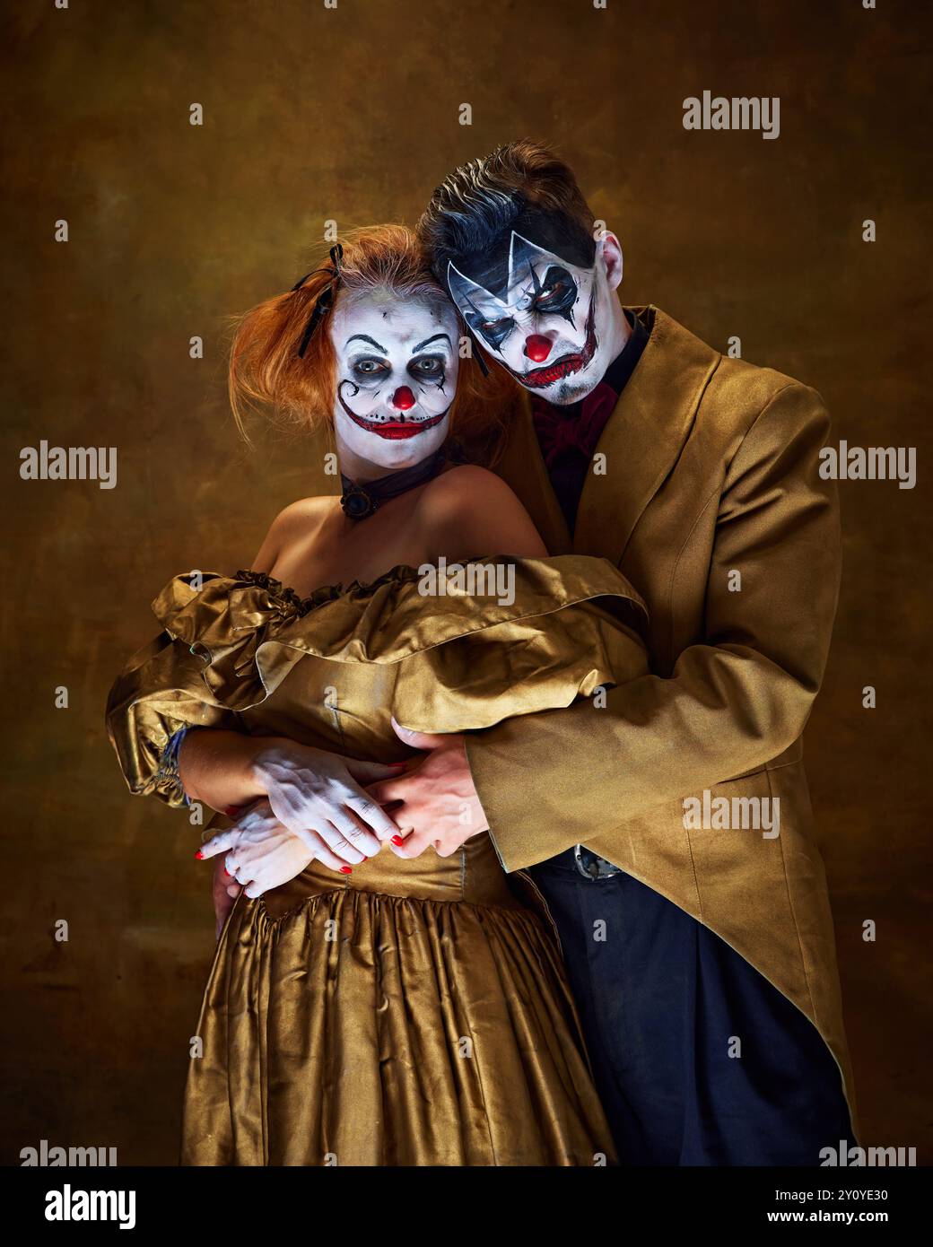 Portrait of two sinister clowns, couple dressed vintage attire hugs ...