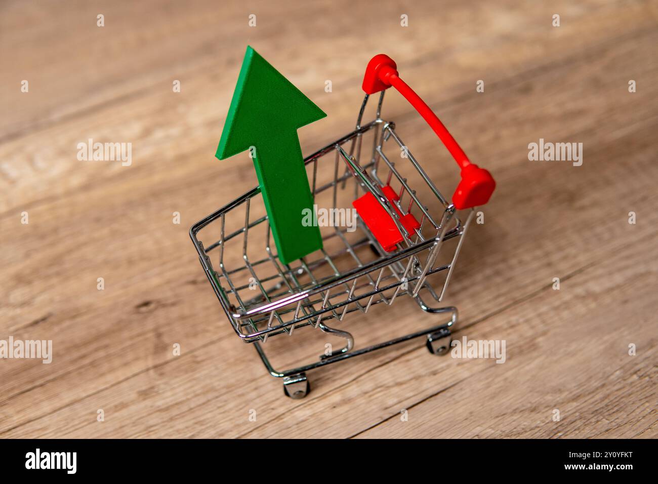 A miniature shopping cart with a large green upward arrow. Economic ...