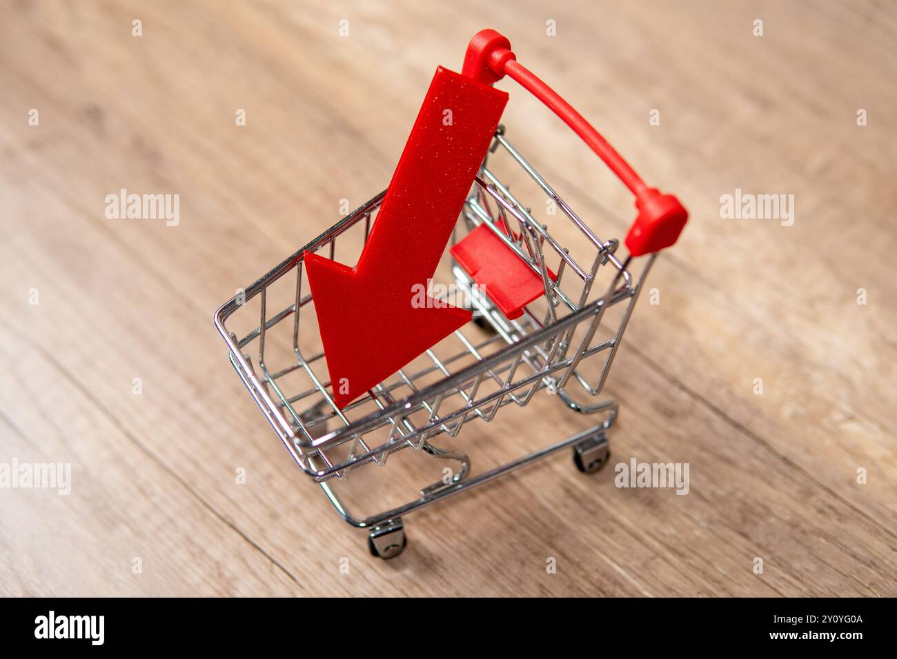 A miniature shopping cart with downward-pointing red arrow. Retail ...