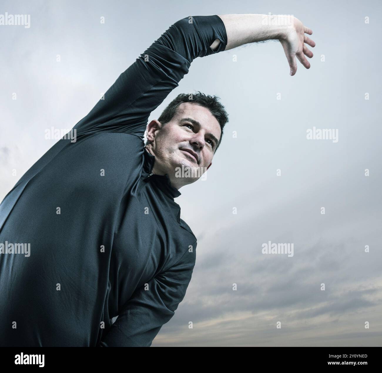 Portrait of man doing stretching exercises outside Stock Photo - Alamy