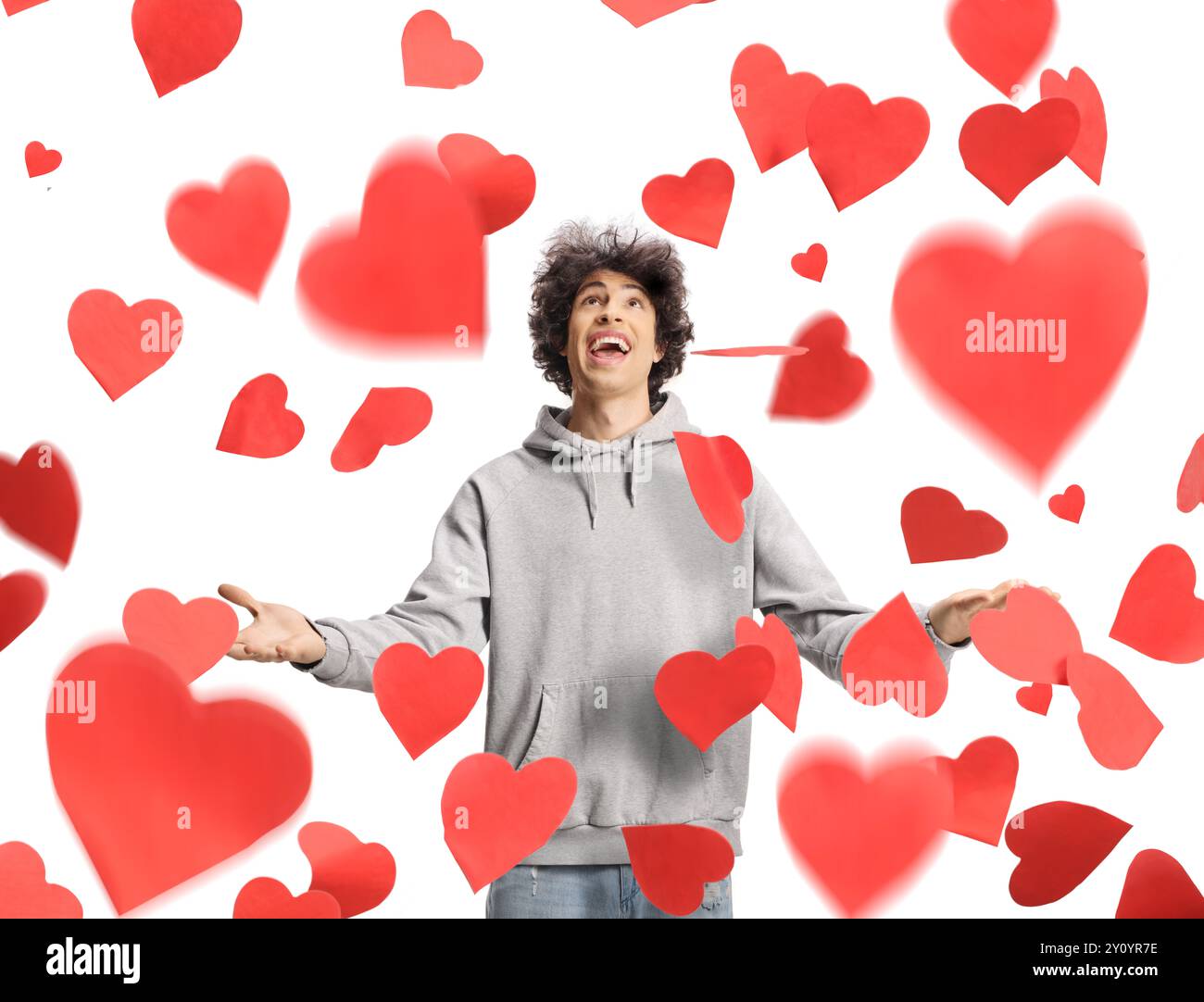 Excited guy in a looking up at red falling hearts isolated on white ...